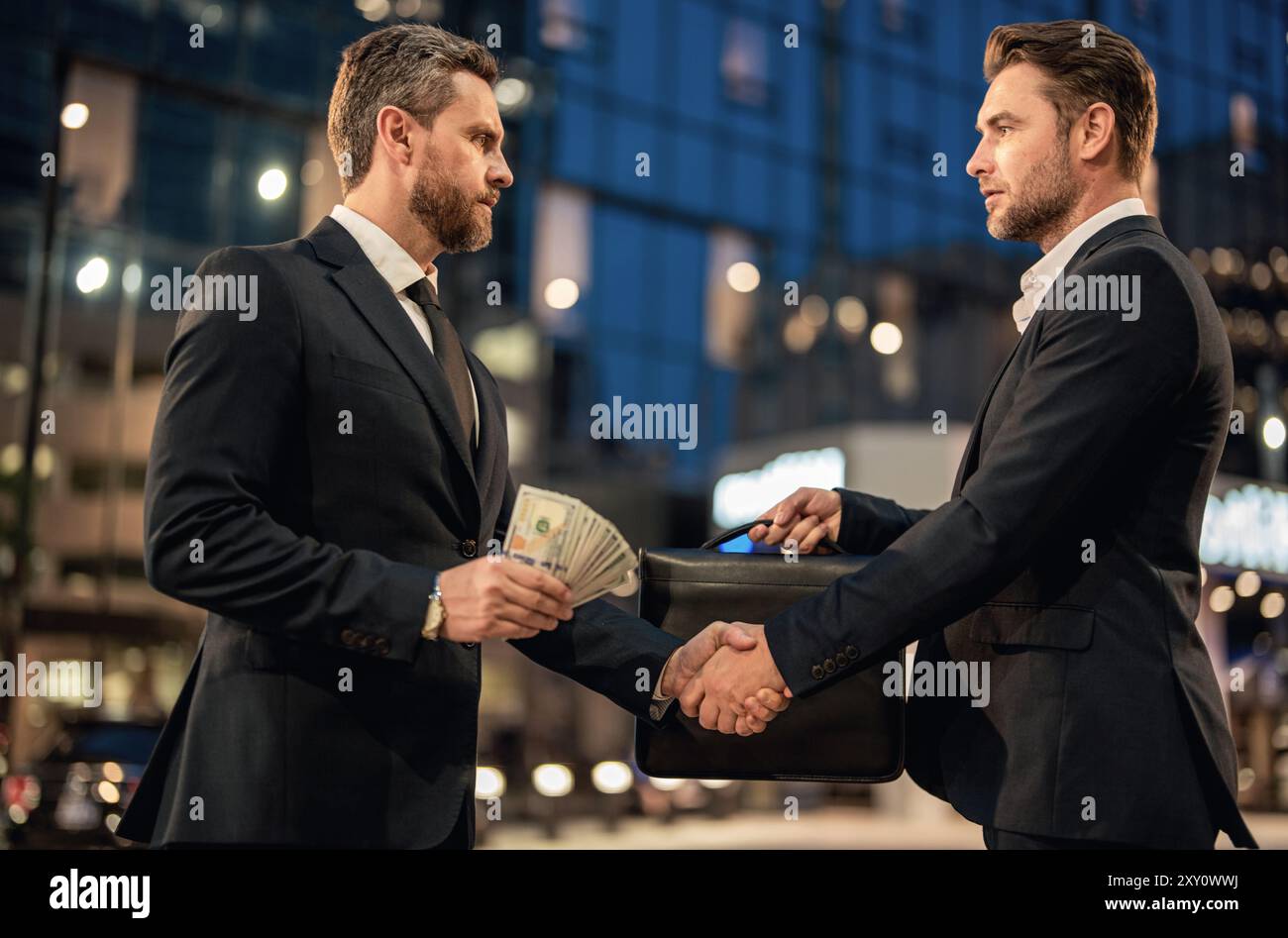 Businessmen shaking hands and receiving banknote. Businessman giving ...