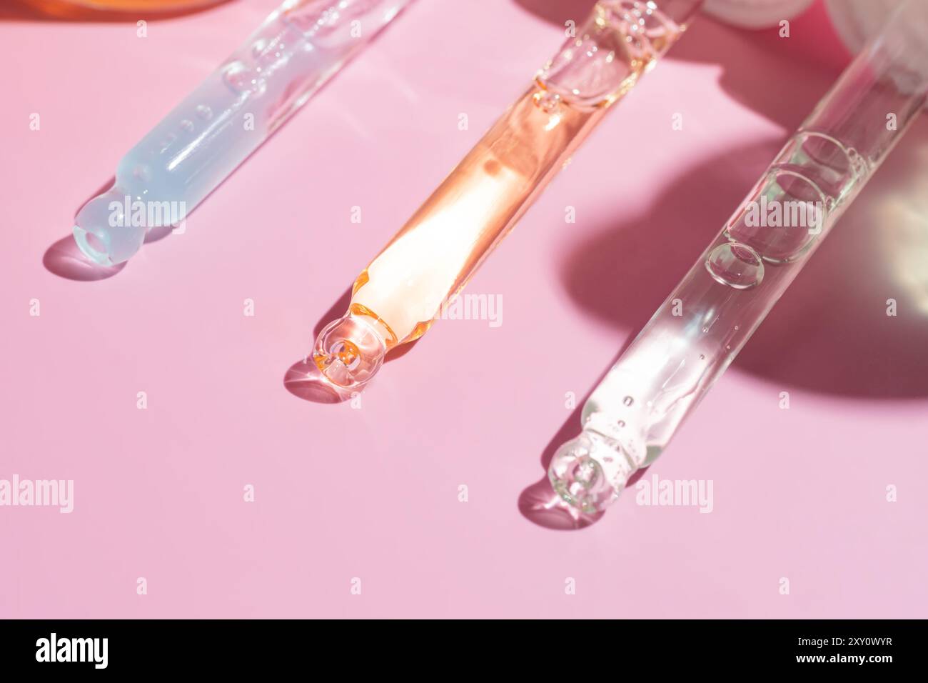 Three translucent serum droppers, each filled with a different colored ...