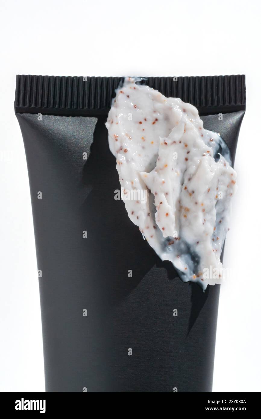 A matte black cosmetic tube with a dab of textured exfoliating cream ...