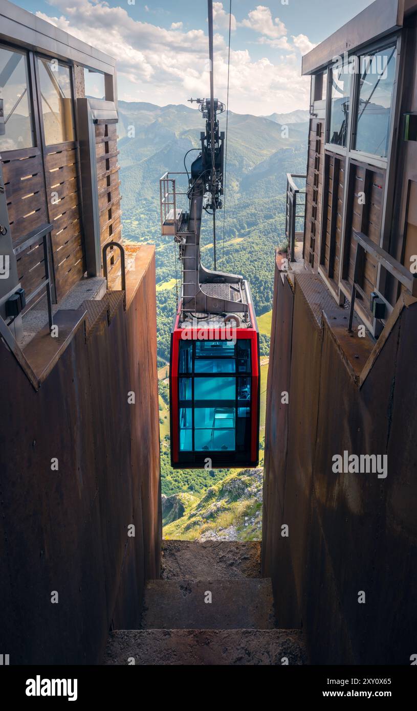 Vibrant red cable car as it ascends over the lush green valleys of ...