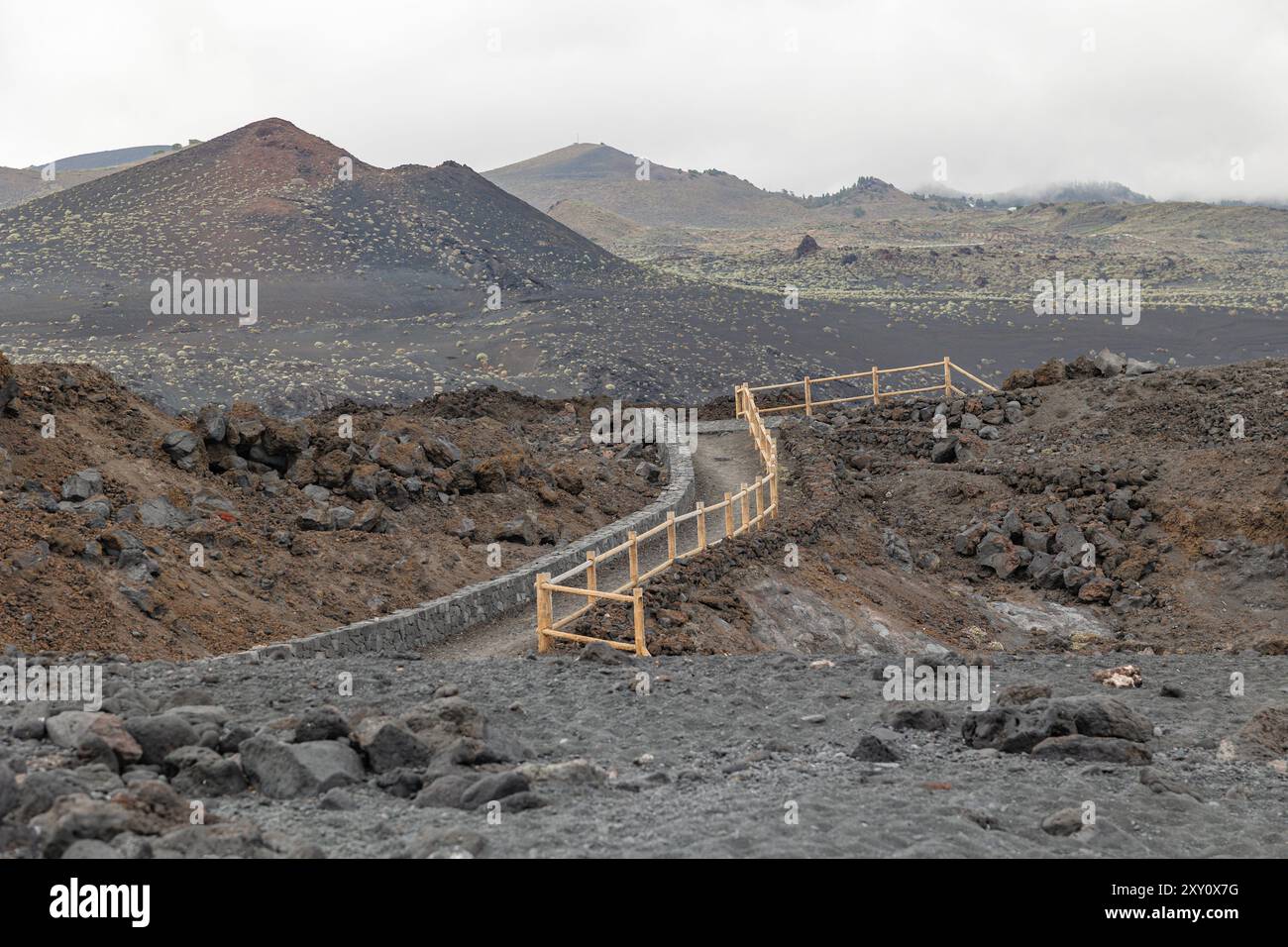A barren volcanic terrain under a gloomy sky, featuring a winding ...