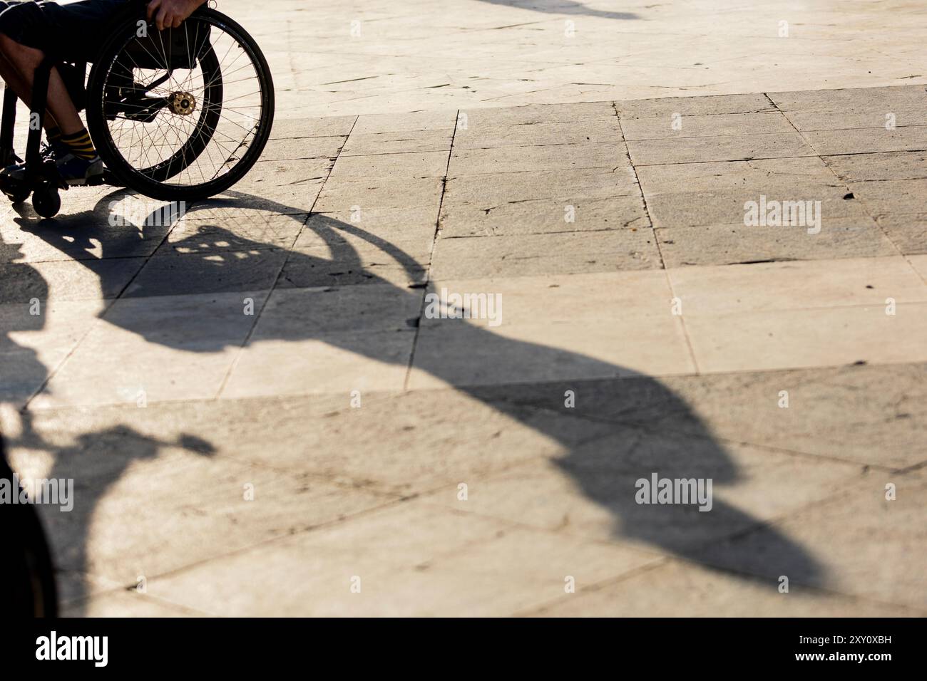 A shadow of a wheelchair user working outdoors, cast on a textured ...