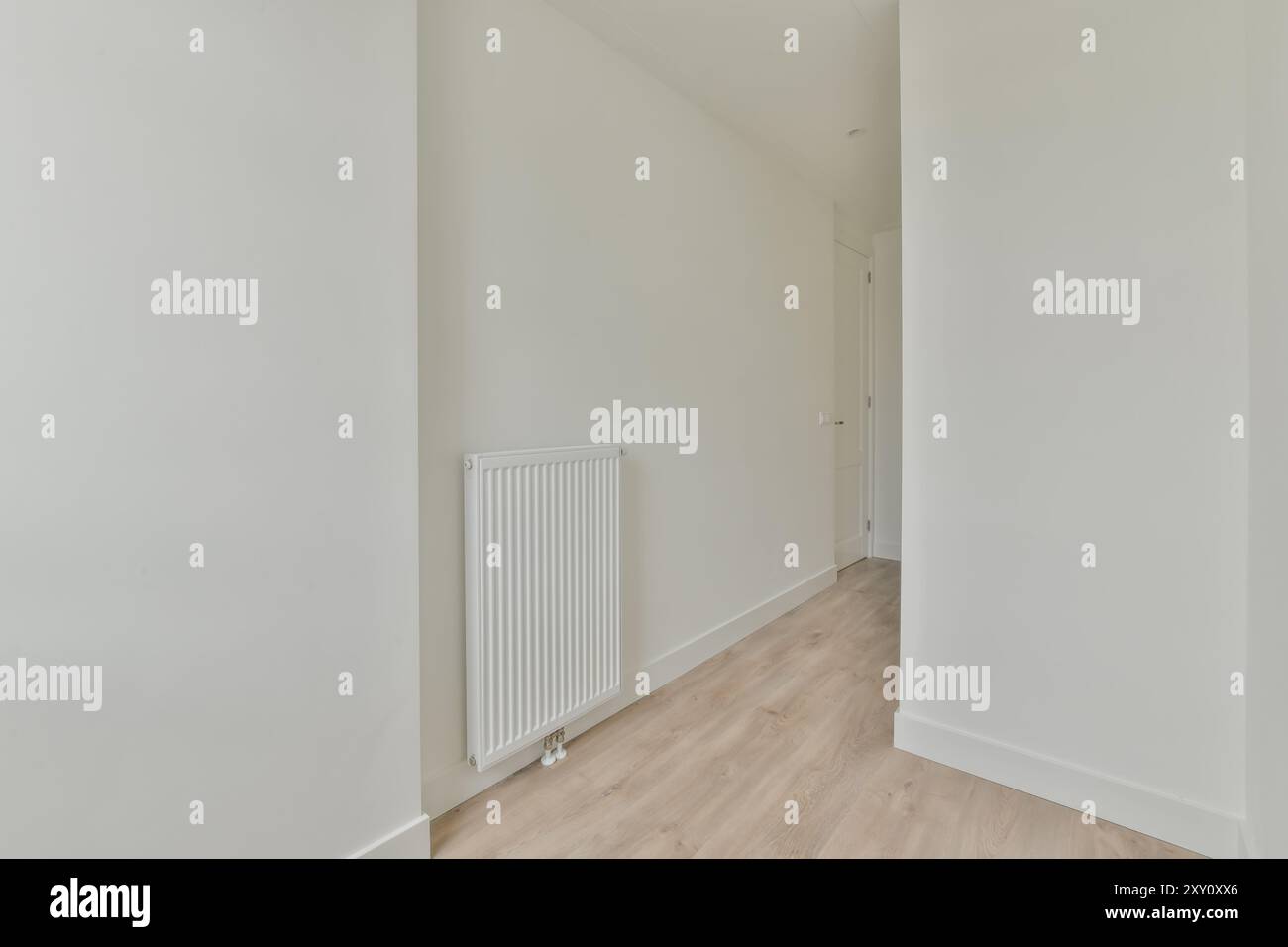 Empty corridor with white walls, a radiator, and wooden flooring Stock ...