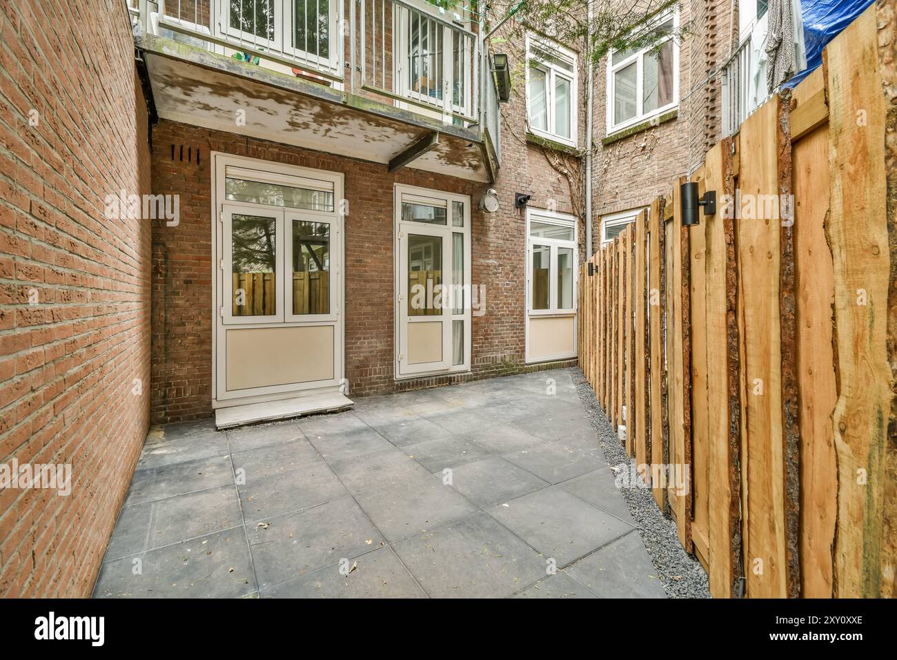 "A paved urban backyard area enclosed by a brick residential building ...