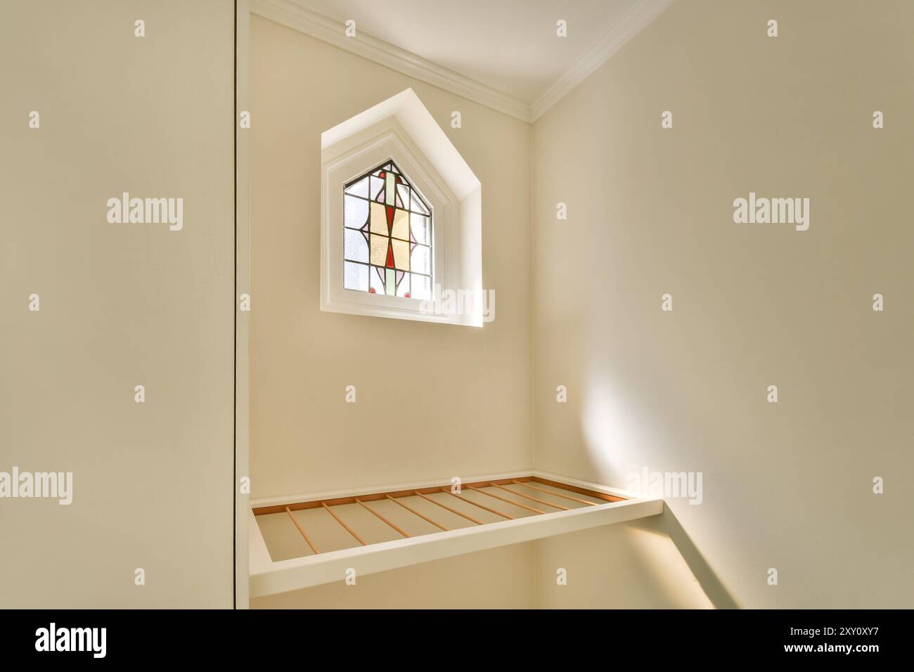 A quaint window seat below a beautiful stained glass window, inviting a ...