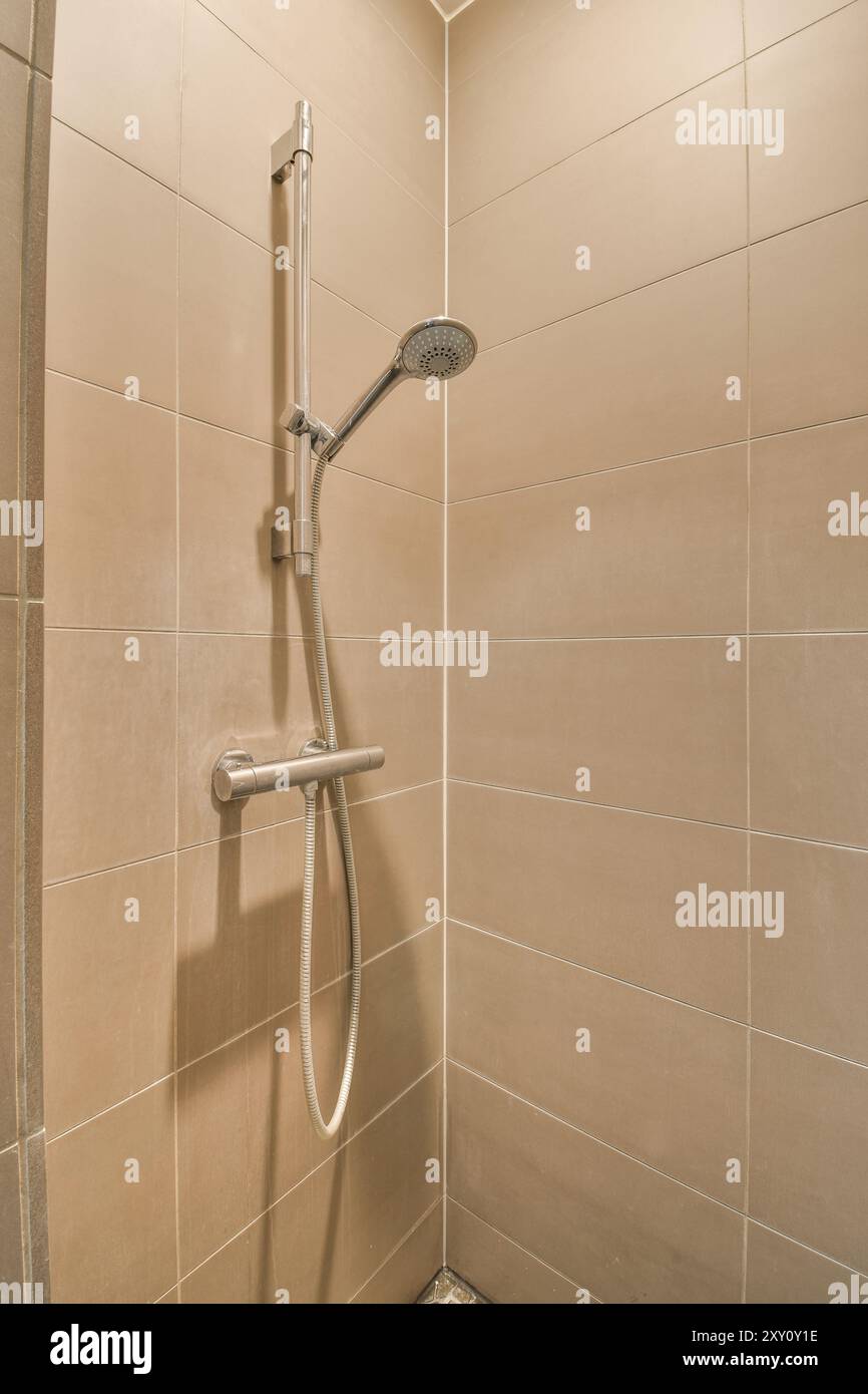 A sleek, adjustable showerhead mounted on a beige-tiled bathroom wall ... A sleek, adjustable showerhead mounted on a beige-tiled bathroom wall ...