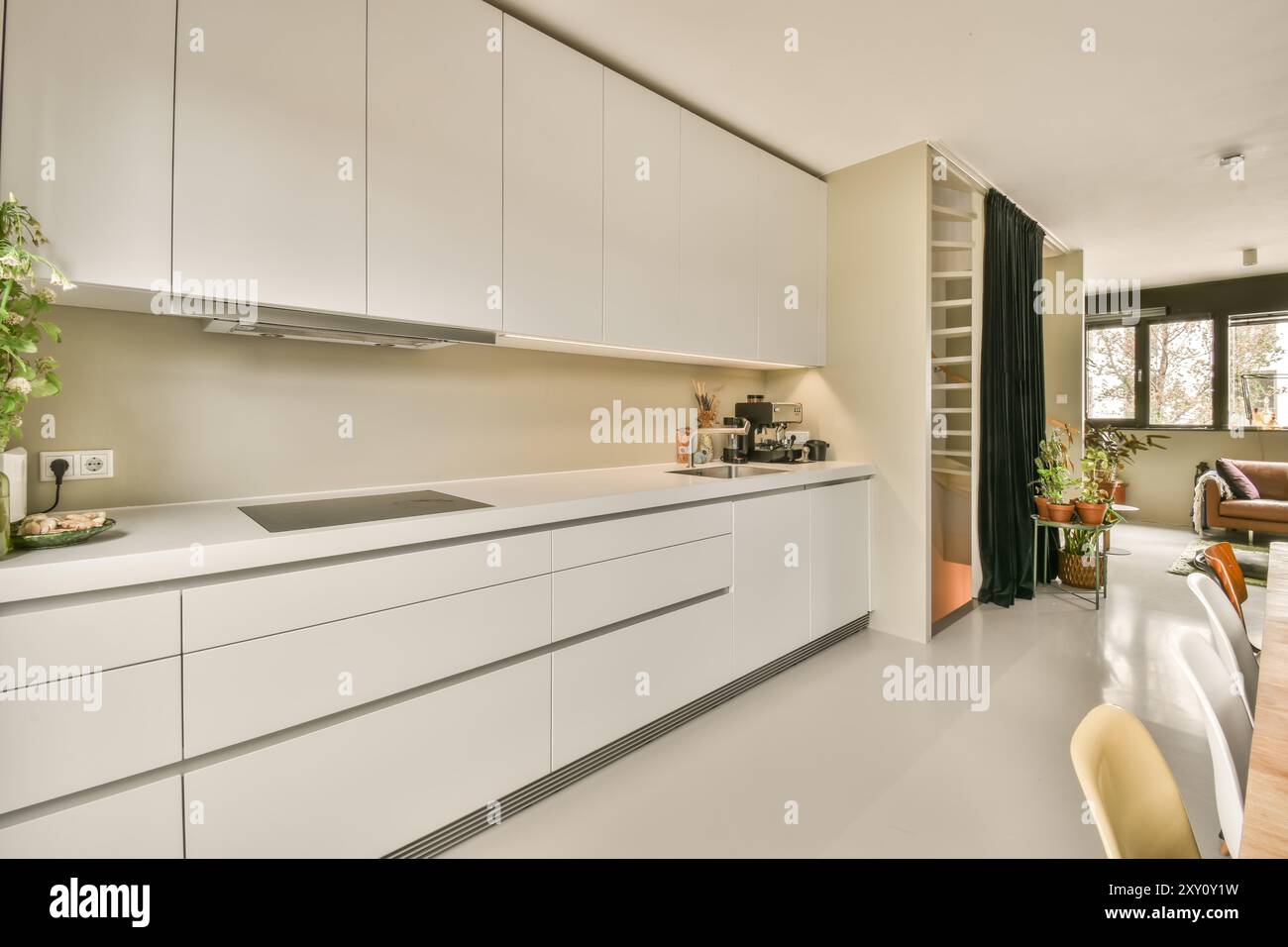 An elegant kitchen with modern white cabinetry, sleek countertops, and ...