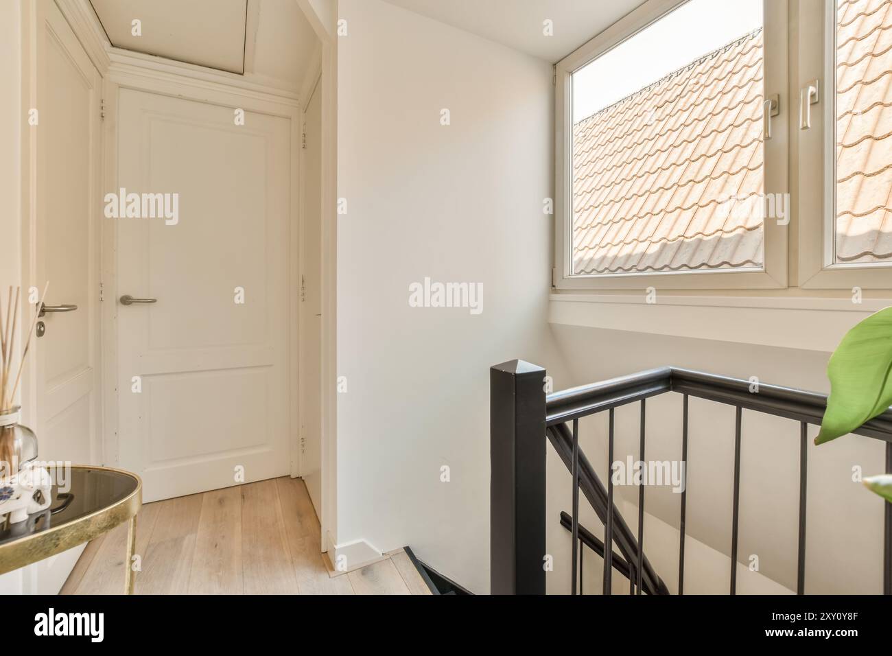 A well-lit, modern stairway corner with a view of a tiled roof outside ...