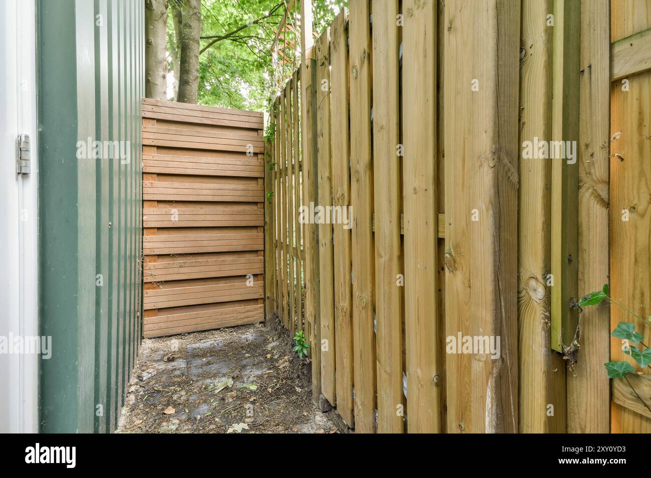 A narrow alley with a new wooden gate next to an old wooden fence ...