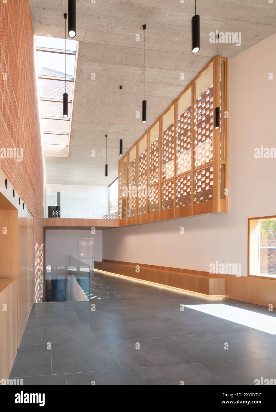 A spacious auditorium lobby featuring wooden paneling, concrete ceiling ...