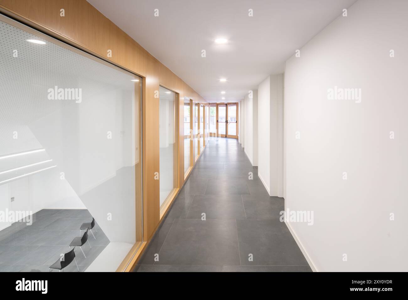 A contemporary and well-lit auditorium corridor featuring wooden doors ...