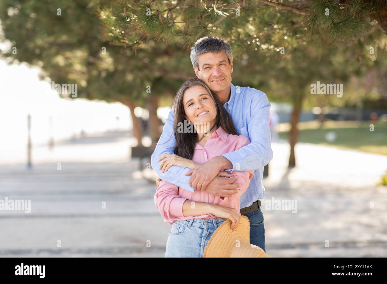 Couple enjoying joyful moment on sunny beach promenade with trees Stock ...