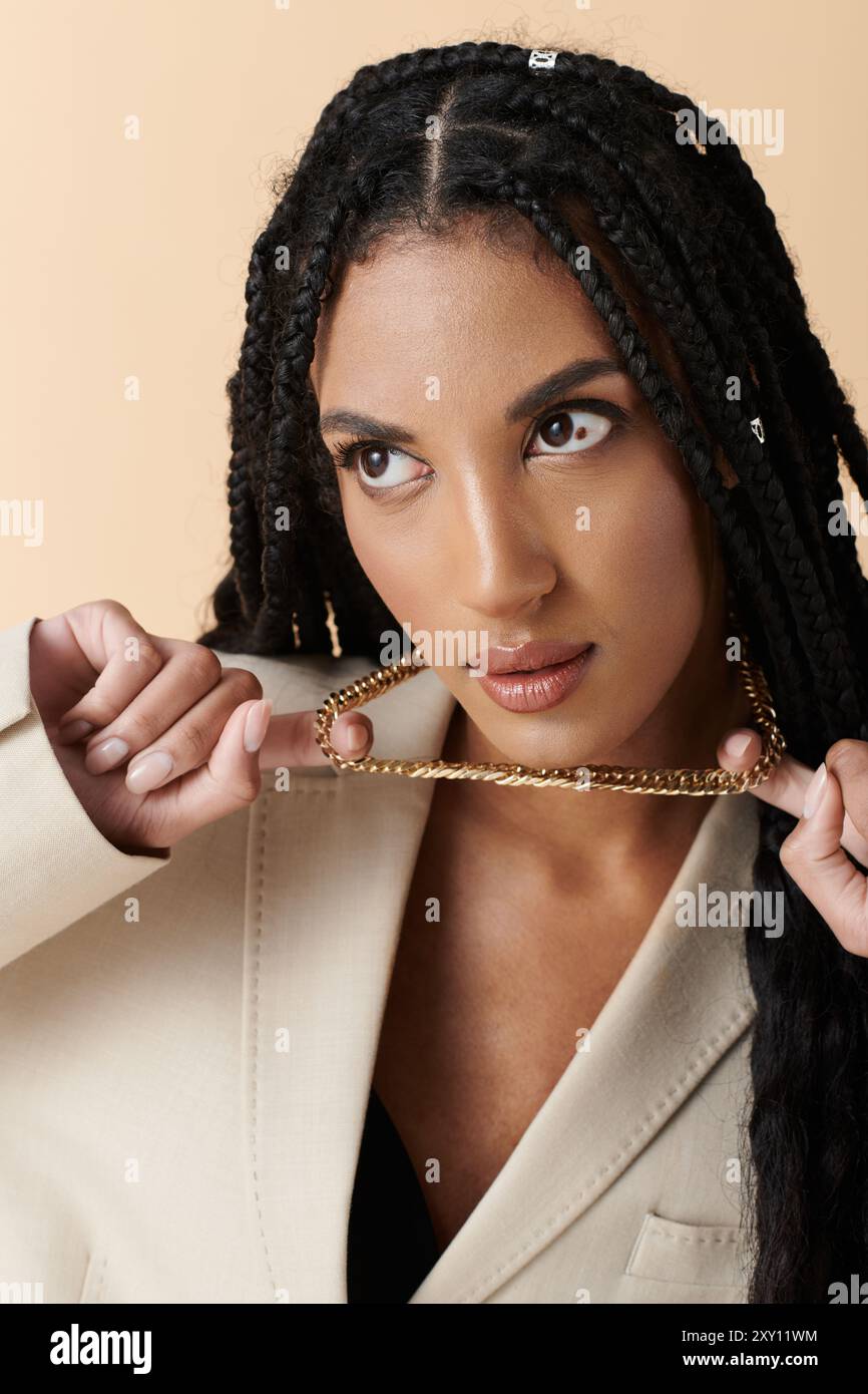 A young African American woman with long braids poses in a beige blazer ...