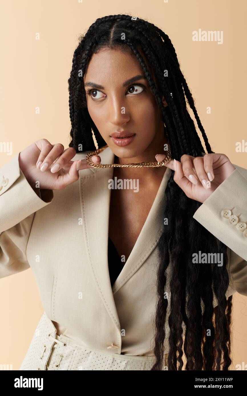 A young woman with braided black hair poses in a beige blazer with a ...