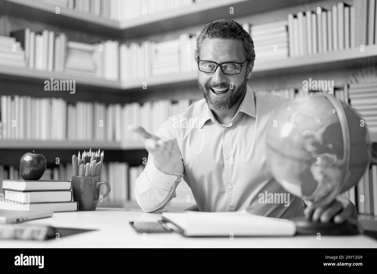 Portrait of school teacher with book in classroom. Handsome teacher in ...