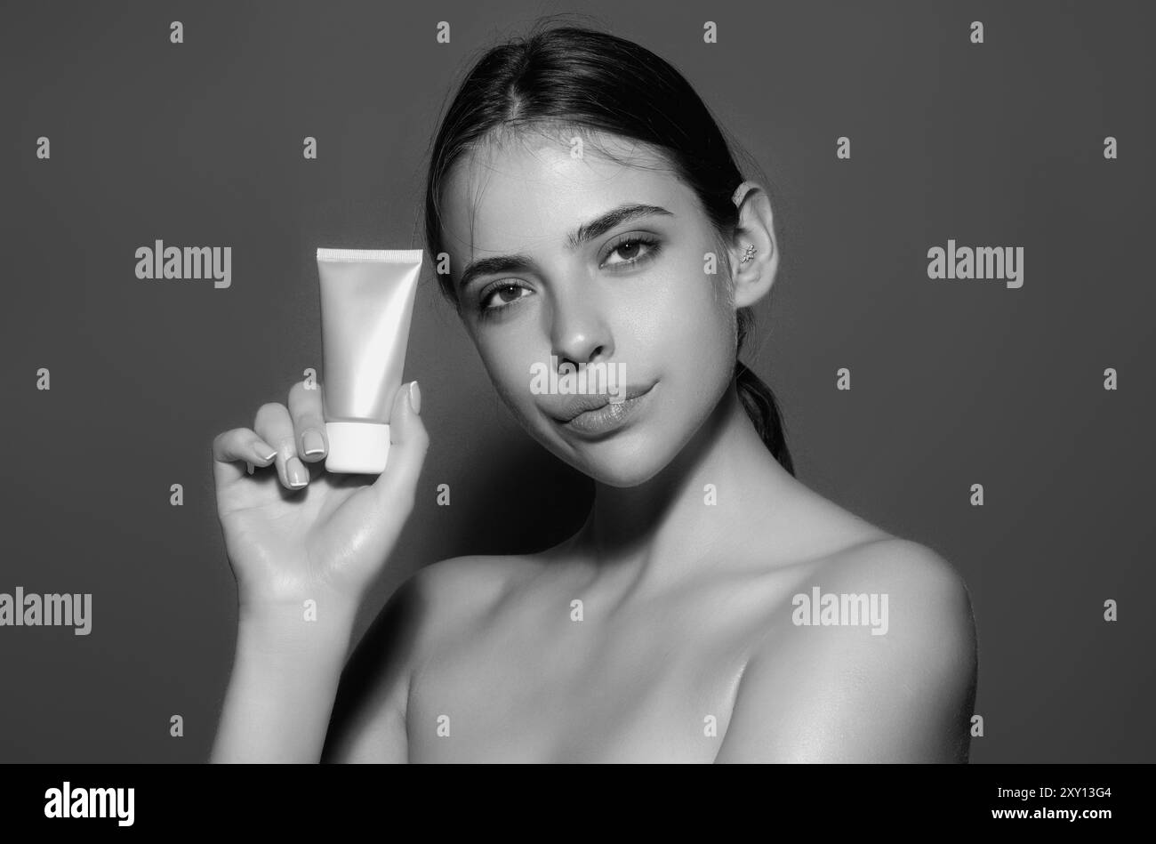 Skin care. Woman applying face cream, studio portrait. Beautiful model ...