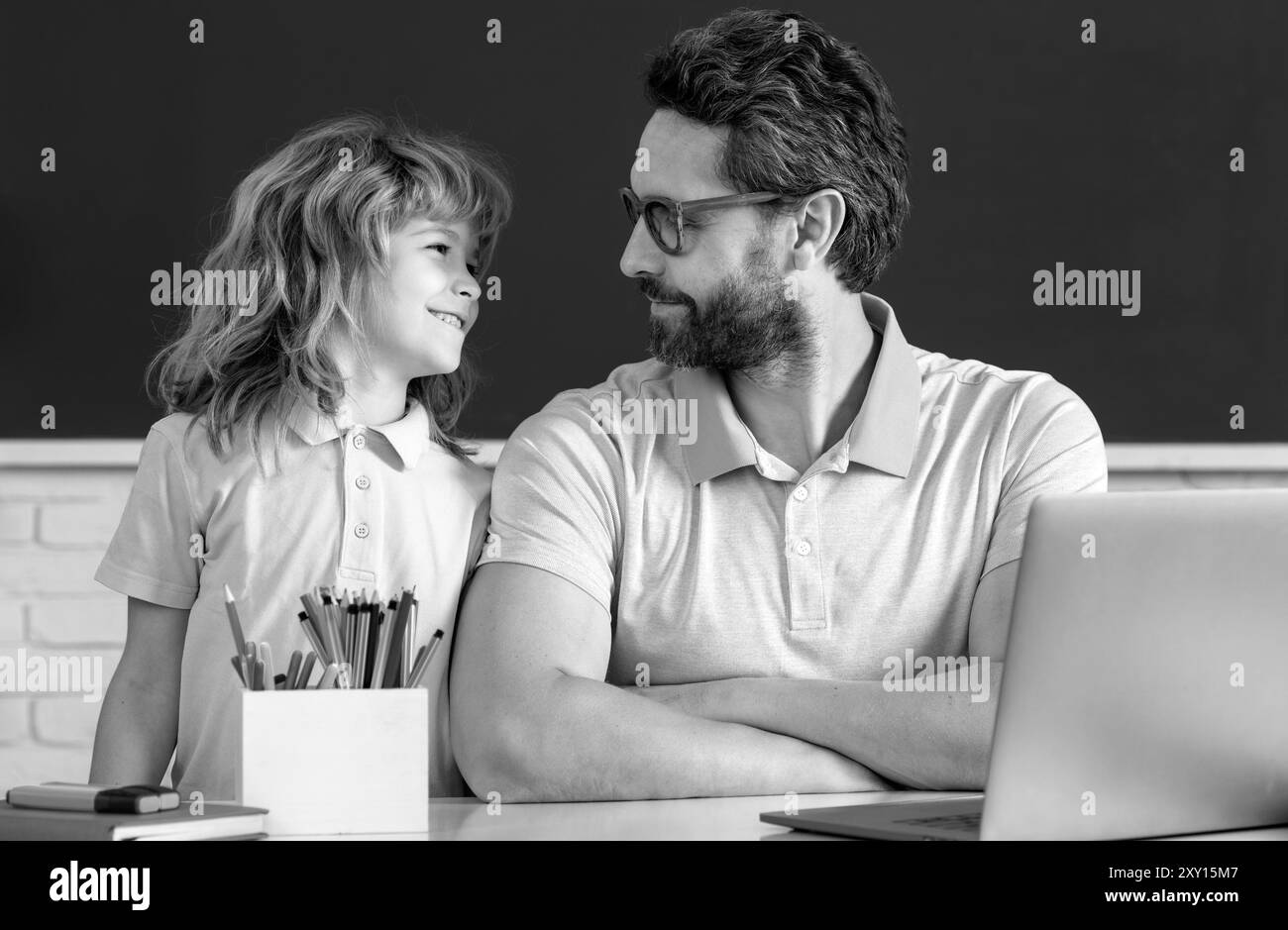 Elementary school boy in classroom on lesson. Teacher explaining to pupil. First day at school ...