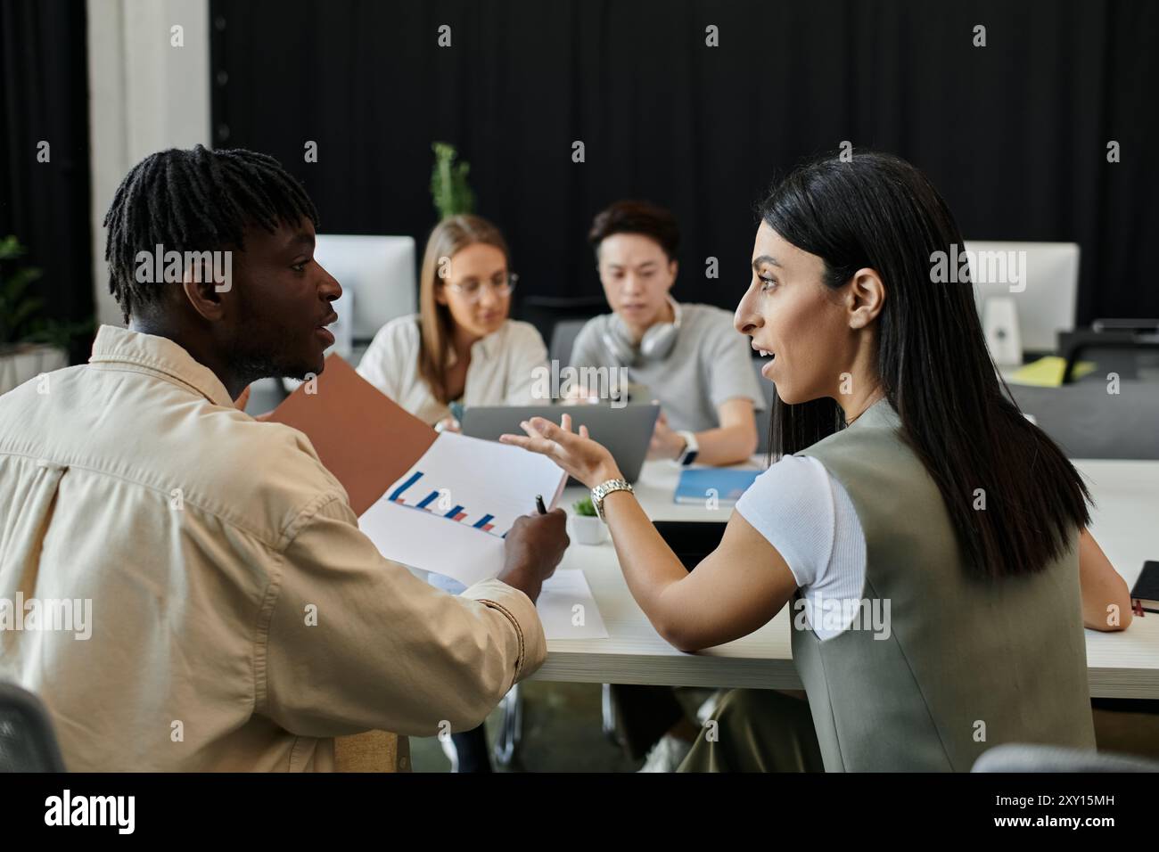 A diverse team of startup employees brainstorm over graphs and charts ...