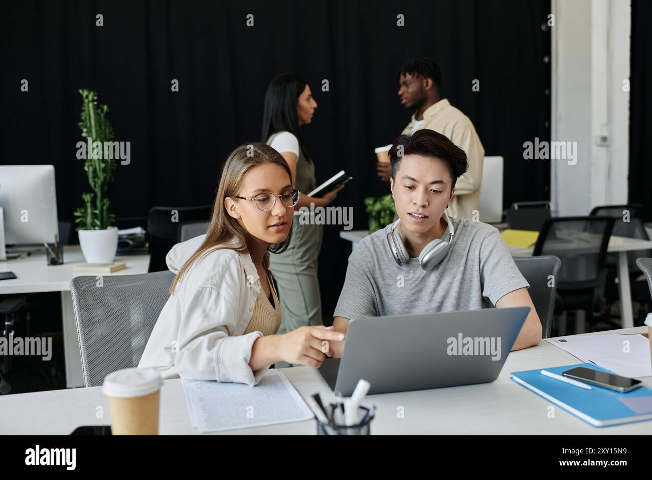 Two young colleagues work together on a laptop, discussing ideas for ...