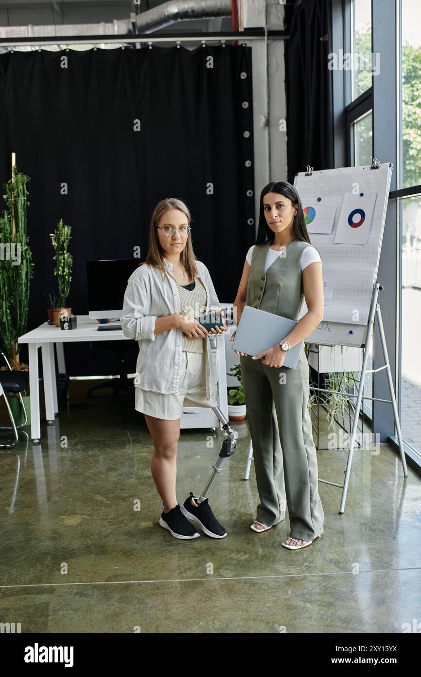 Two women stand in a modern office, collaborating on a project Stock ...