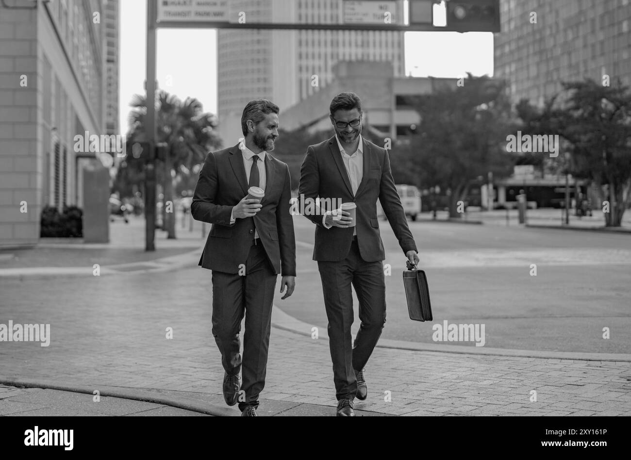 Two attractive confident hispanic businessmen in suits walking outdoors ...