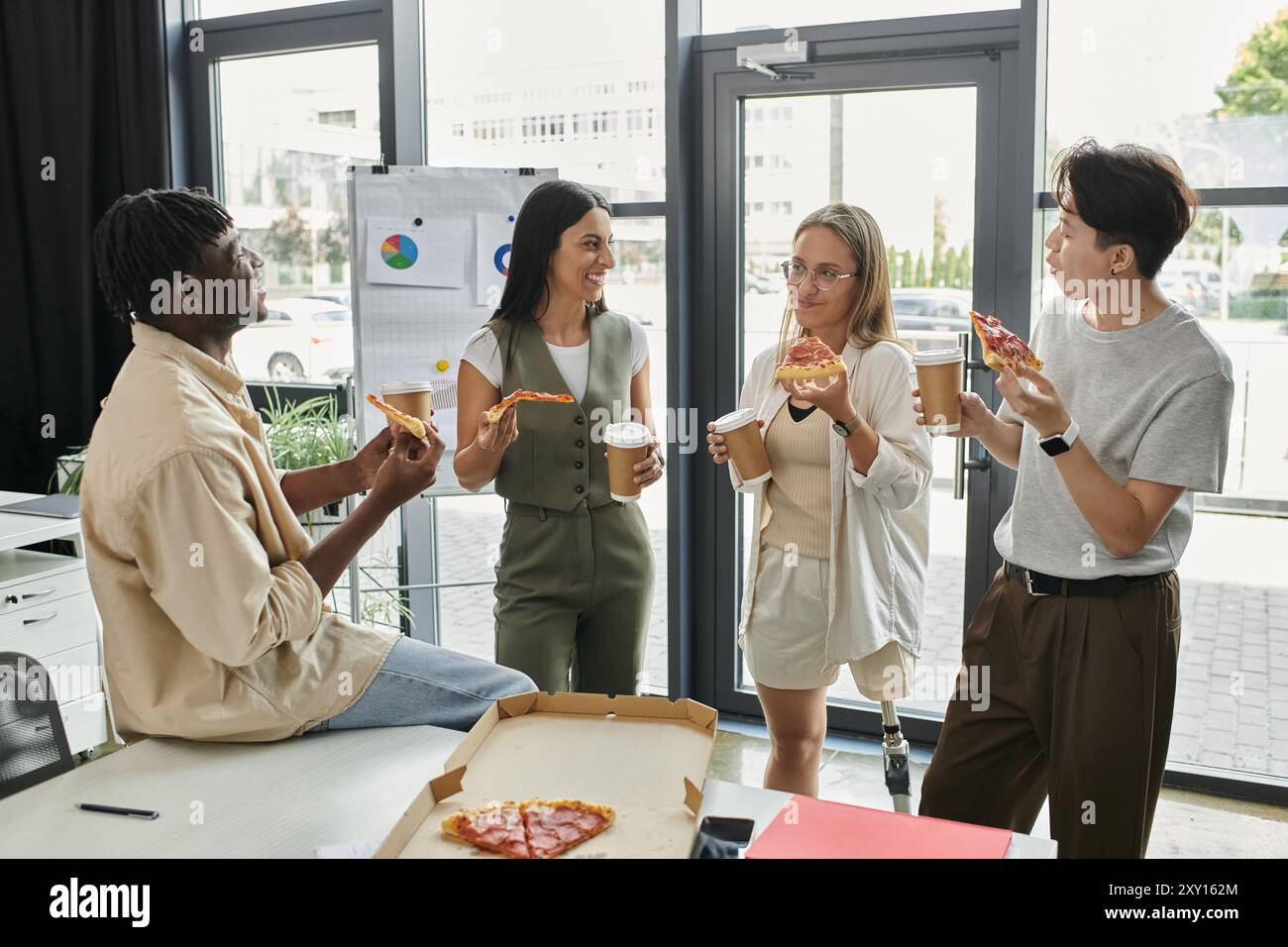 Four colleagues enjoy pizza and coffee during a break in their workday ...