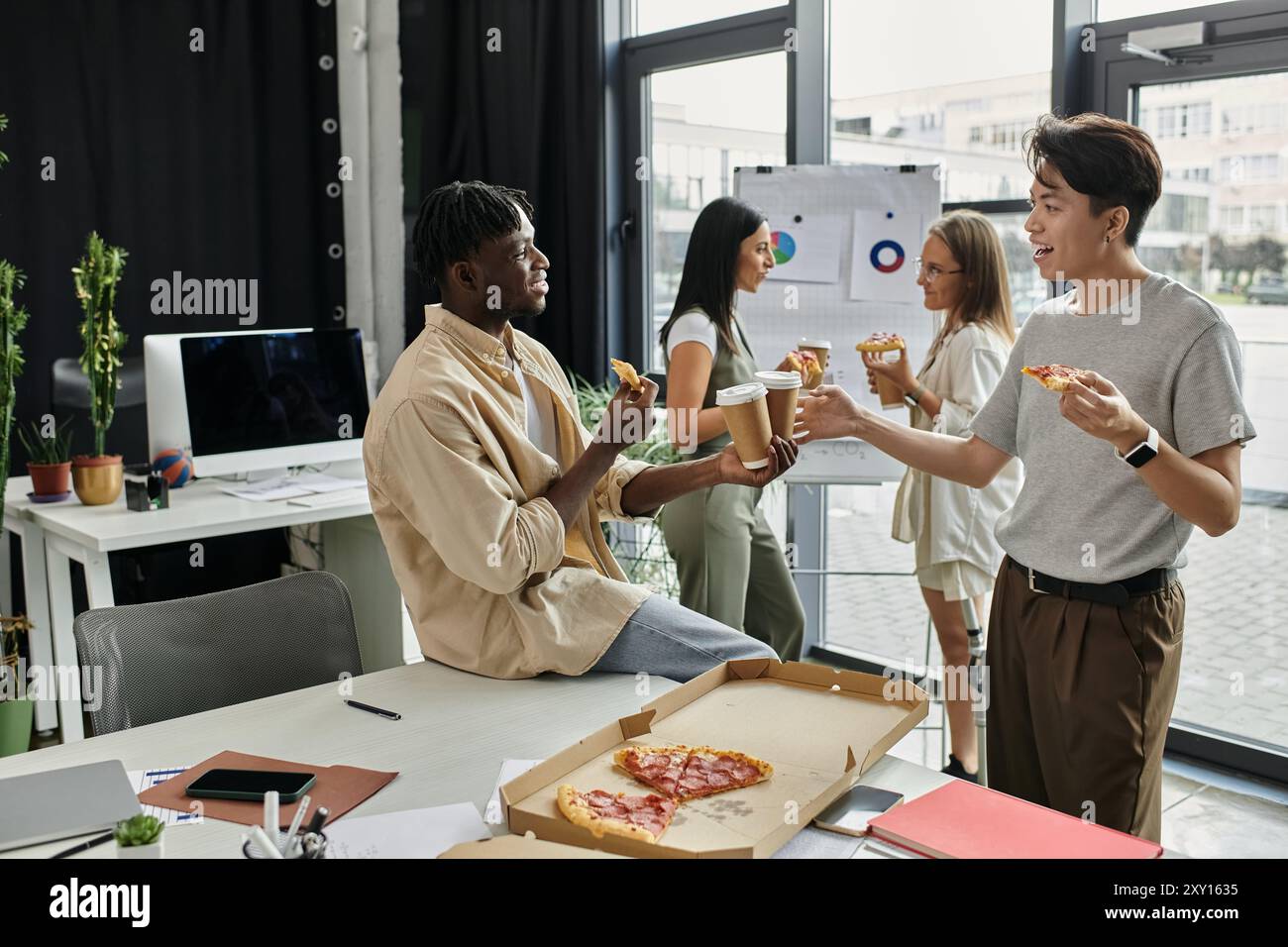 Four young colleagues take a break from work, enjoying pizza and coffee ...