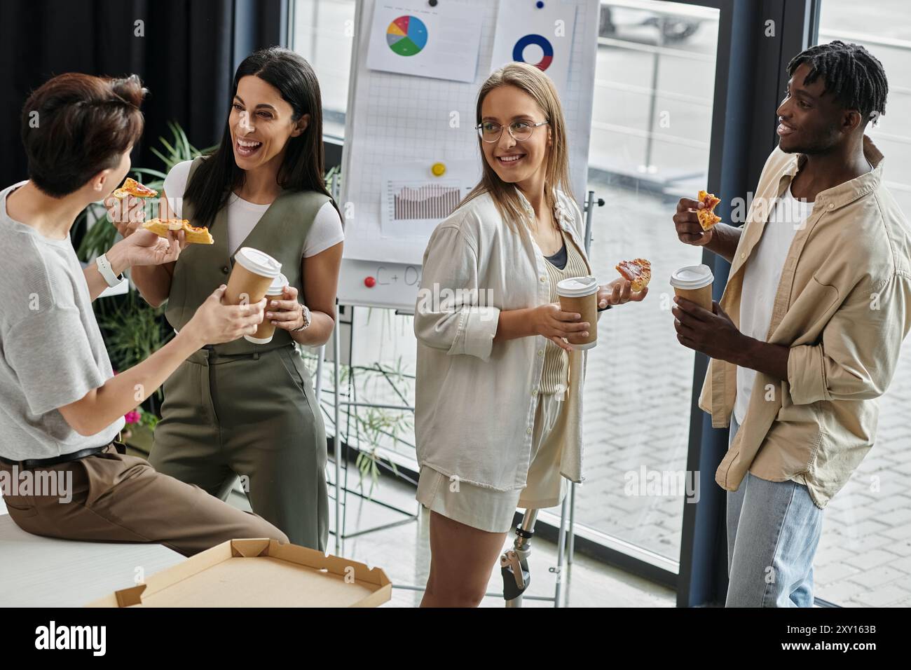 Four colleagues enjoy a casual lunch break with pizza and coffee Stock ...
