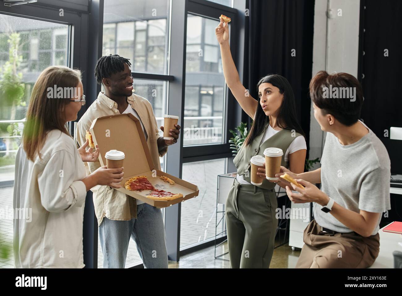 Four coworkers enjoy a pizza break during their work day, laughing and sharing slices Stock ...