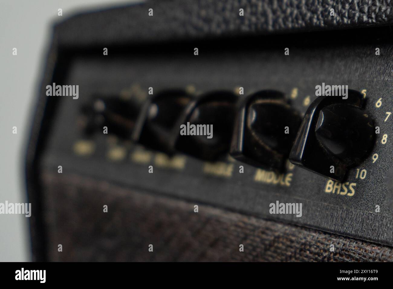 Close-up of black guitar amplifier knobs with numbers on a textured ...