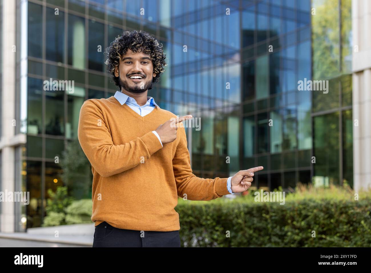 Indian businessman smiling confidently while pointing at modern office ...