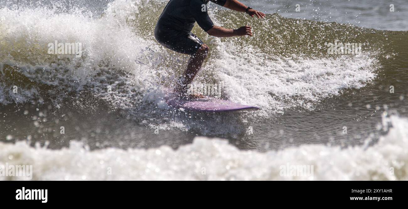 Front view of a man surfing on a purple surfbord in a rough Atlantic ...