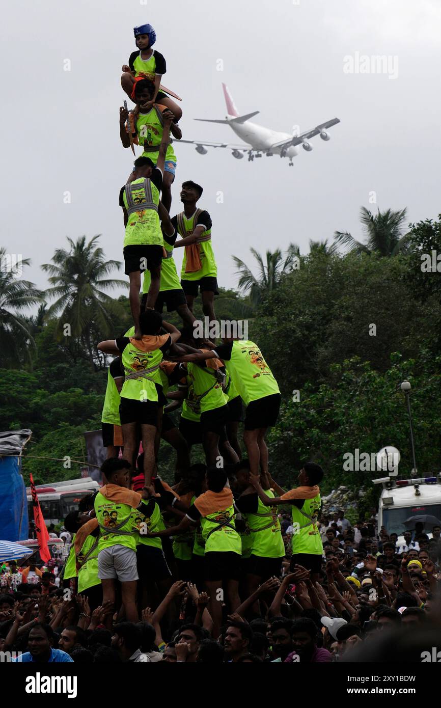 A plain flies as revelers form human pyramids to reach an overhanging ...