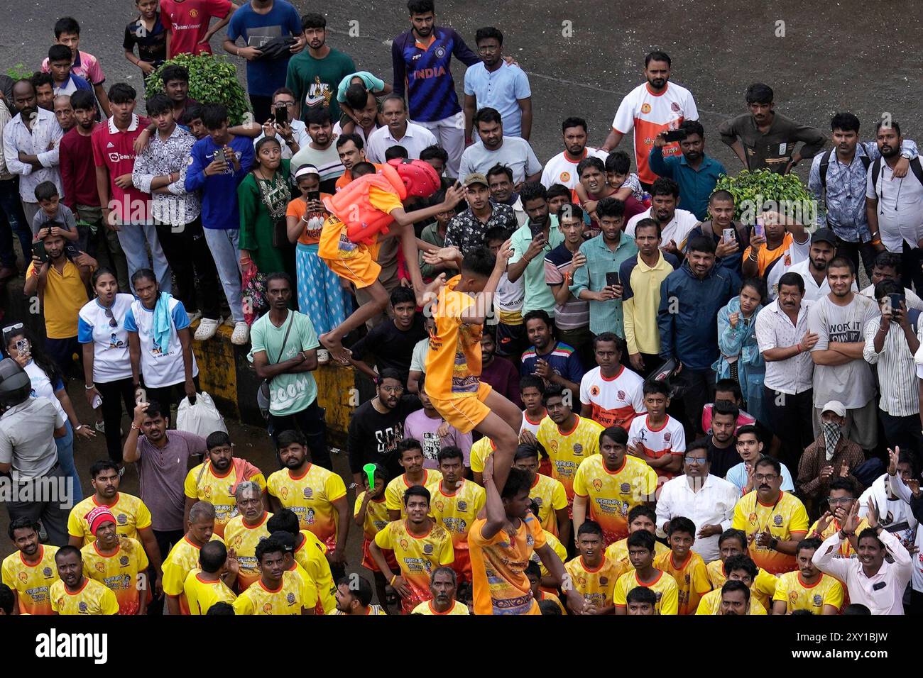 Revelers fall form human pyramids to reach an overhanging earthen pot ...