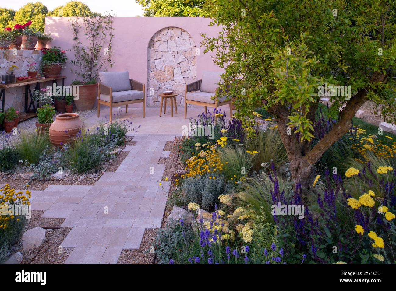 A limestone feature wall behind a paved terrace and path surrounded by ...