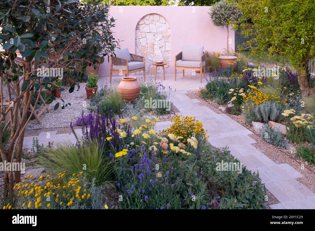 A limestone feature wall behind a paved terrace and path surrounded by ...