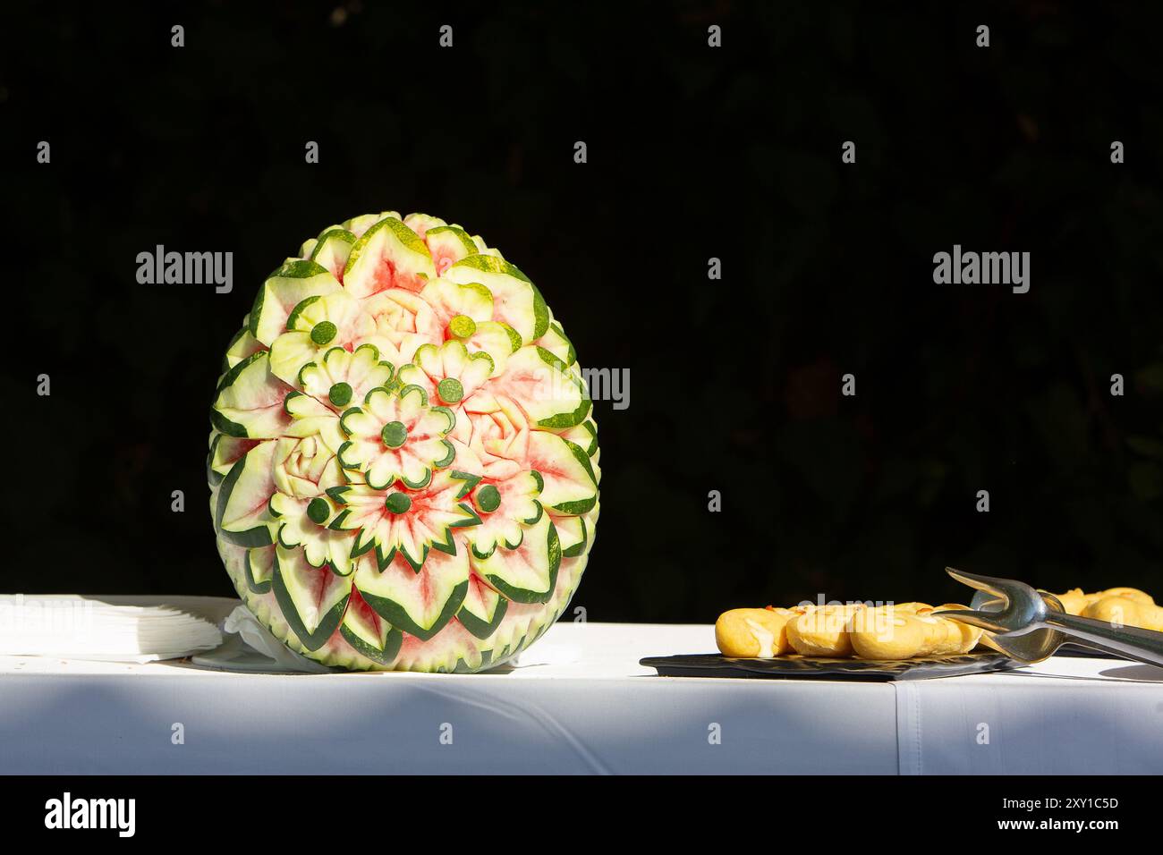Intricately carved watermelon centerpiece on table with appetizers in ...