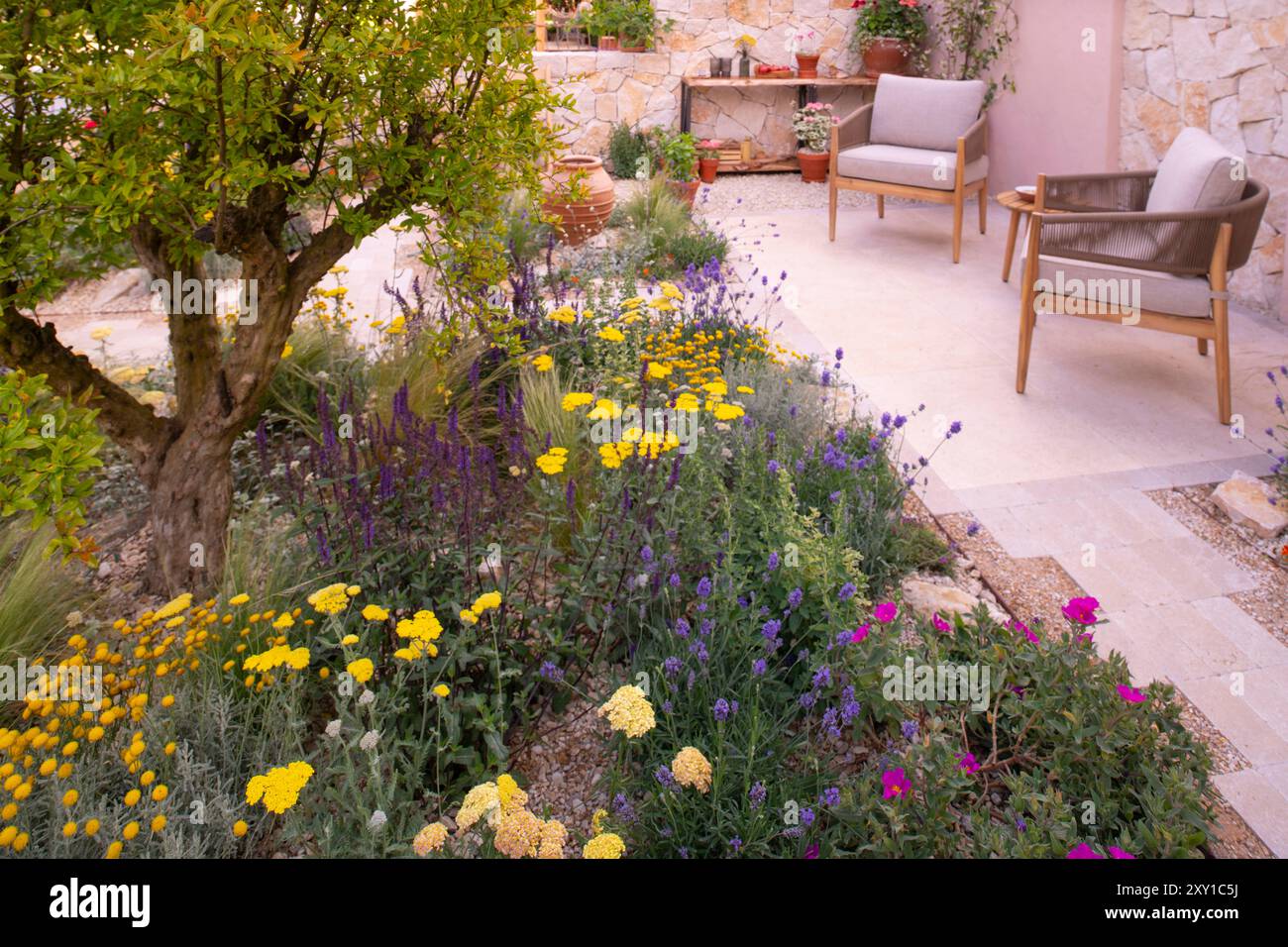 A limestone feature wall behind a paved terrace and path surrounded by ...