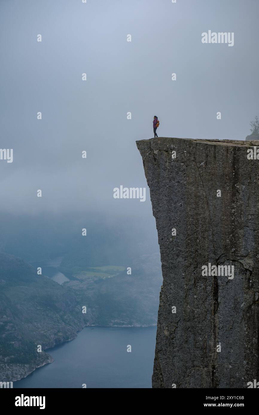 A lone hiker stands triumphantly on a cliff edge, gazing into the ...