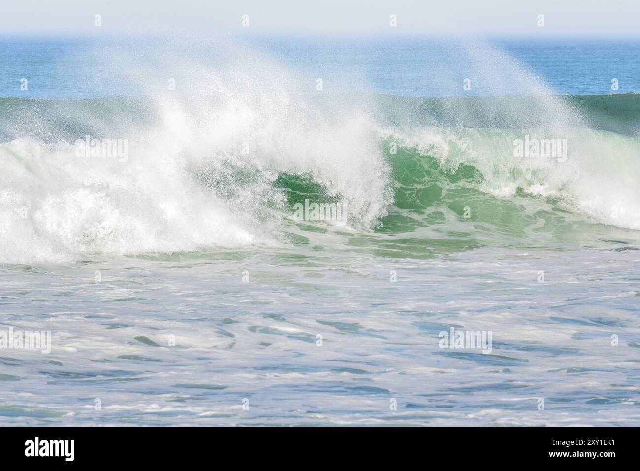 Breaking huge ocean wave sending up plumes of spray on a windy day ...
