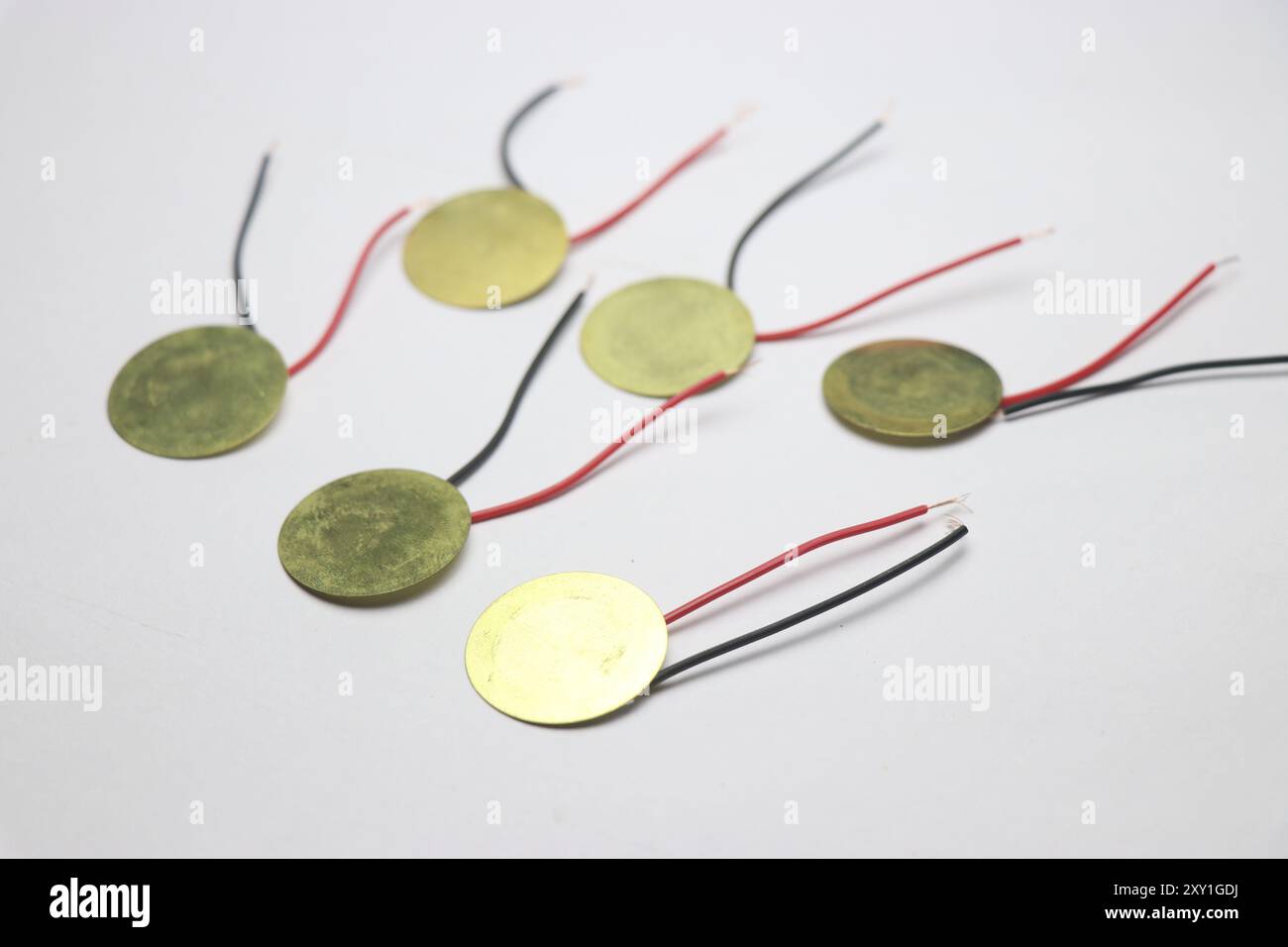 Piezoelectric discs with wires soldered made of copper on a white ...
