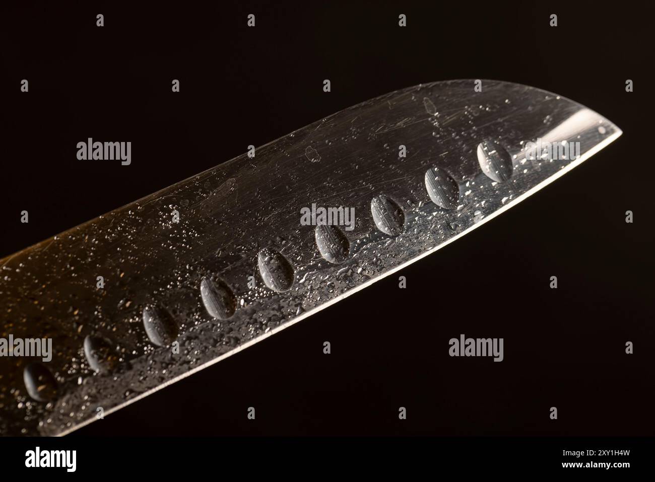 a steel knife covered with water droplets on a blackboard background ...