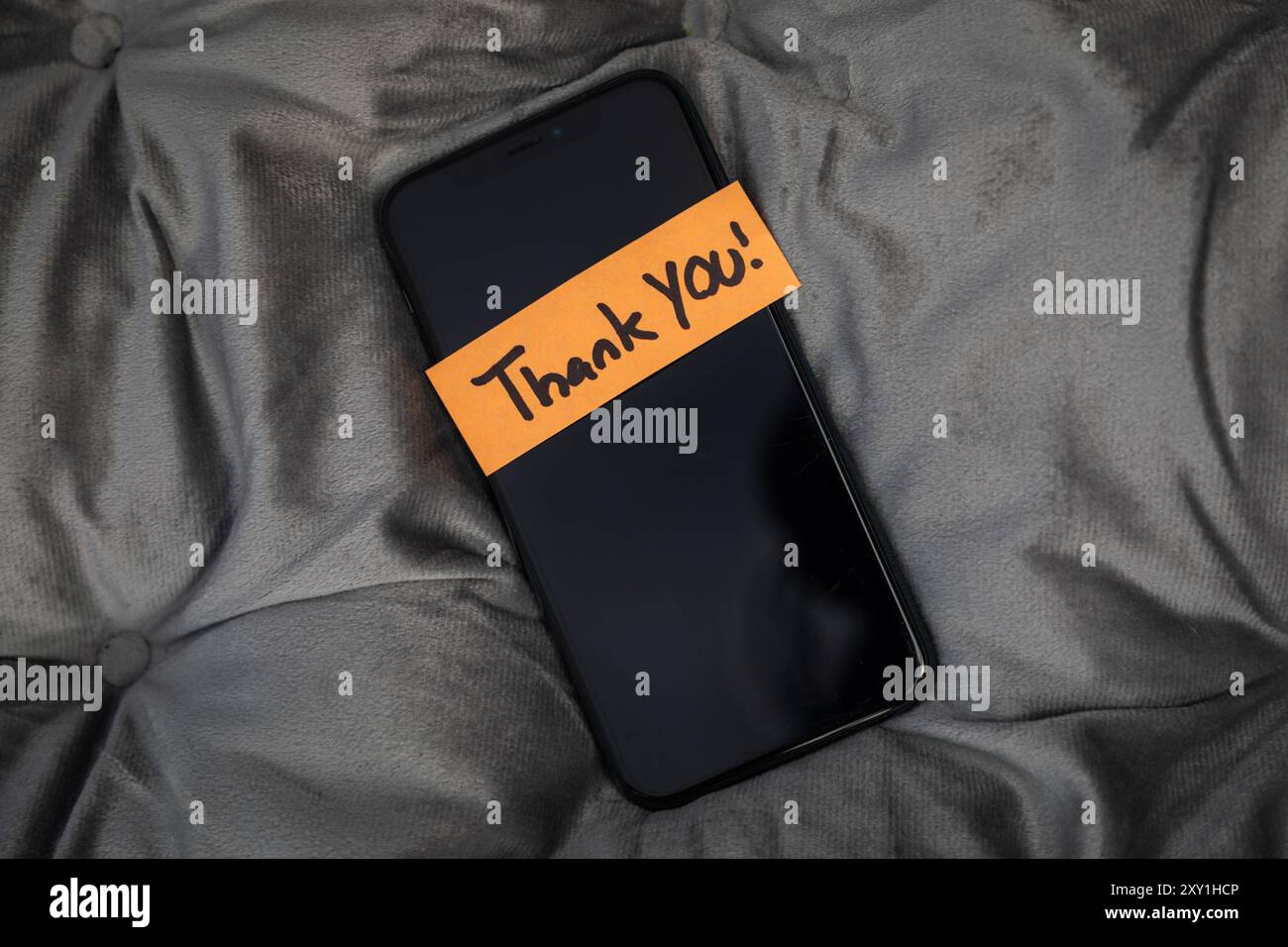 A cell phone with a note on it that says "Thank You". The phone is ...