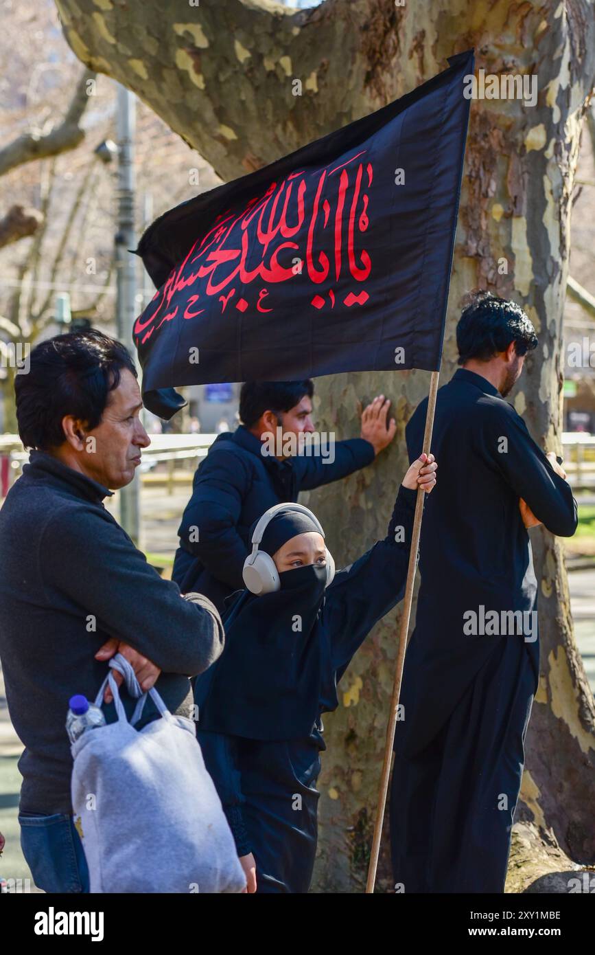 A young Muslim girl with headphones and a flag seen during Arbaeen ...