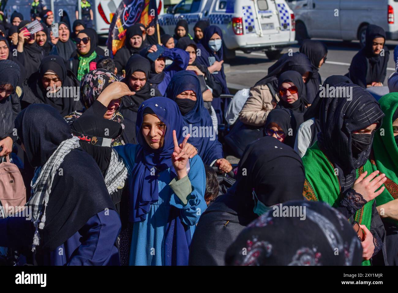 A girl in a headscarf poses with a peace sign hand gesture during ...