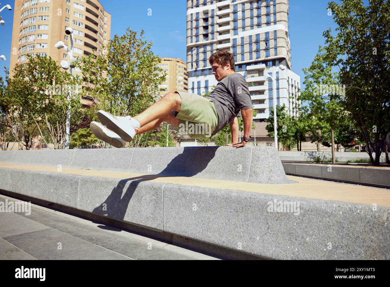 Young sports man training in city park, balancing on hands with legs ...