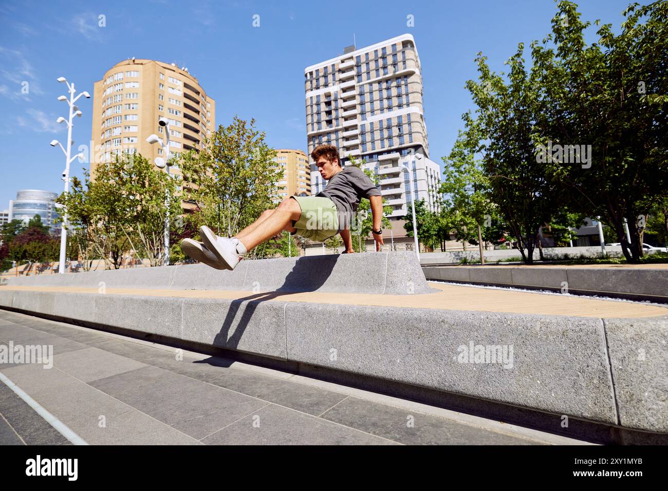 Young sports man training in city park, balancing on hands with legs ...