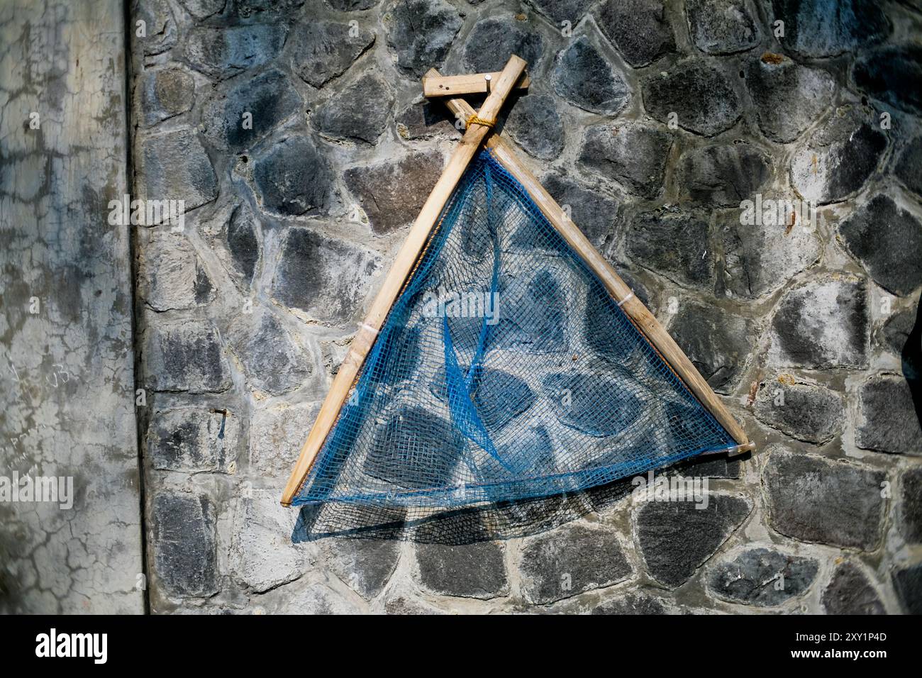 A triangular fishing net hangs on the wall Stock Photo - Alamy