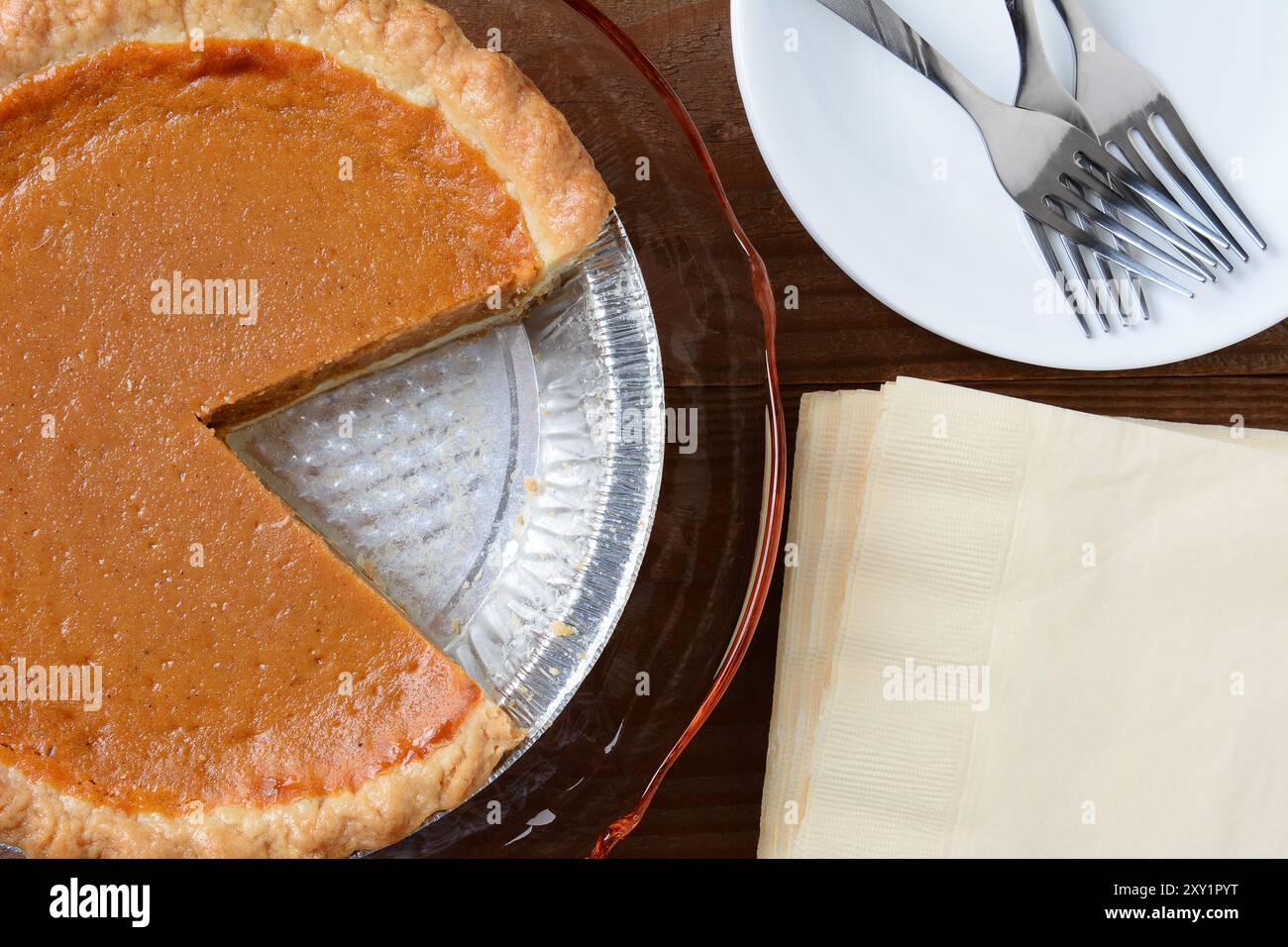 Top view of a fresh pumpkin pie with a slice missing with napkins ...