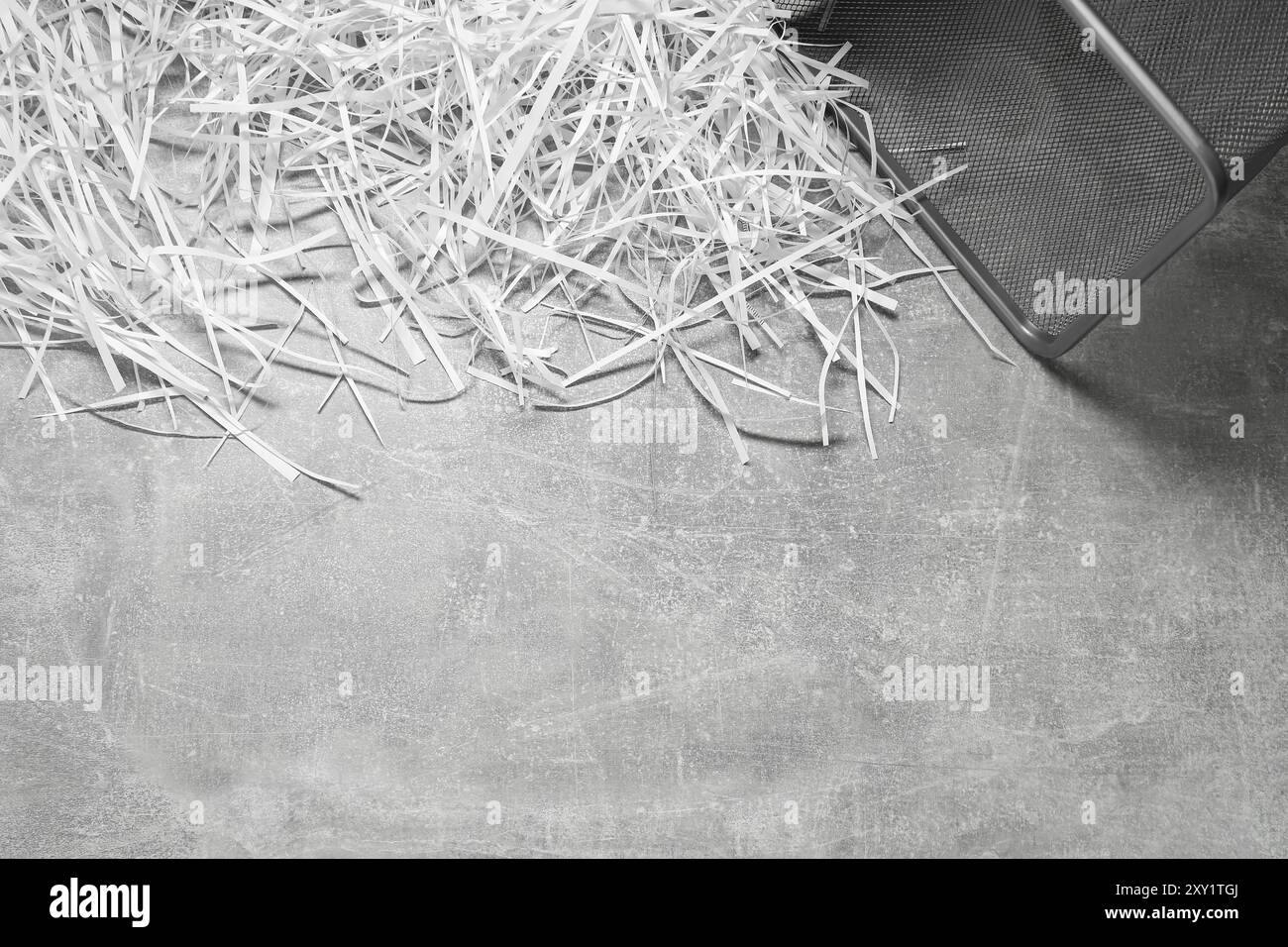 Shredded paper strips with trash bin on grey textured table, top view ...